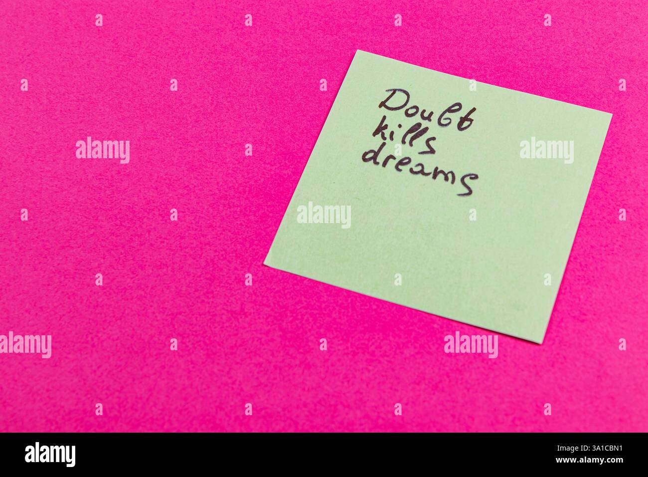 A green sticky note with the message Doubt kills dreams is placed on a ...