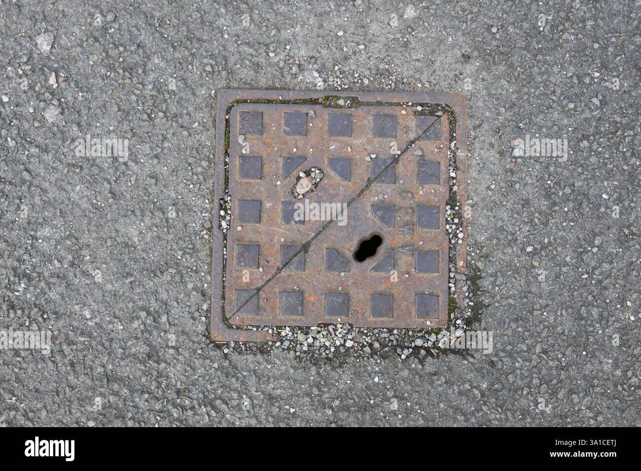 A metal grate is sitting on the ground. The grate is square in shape ...