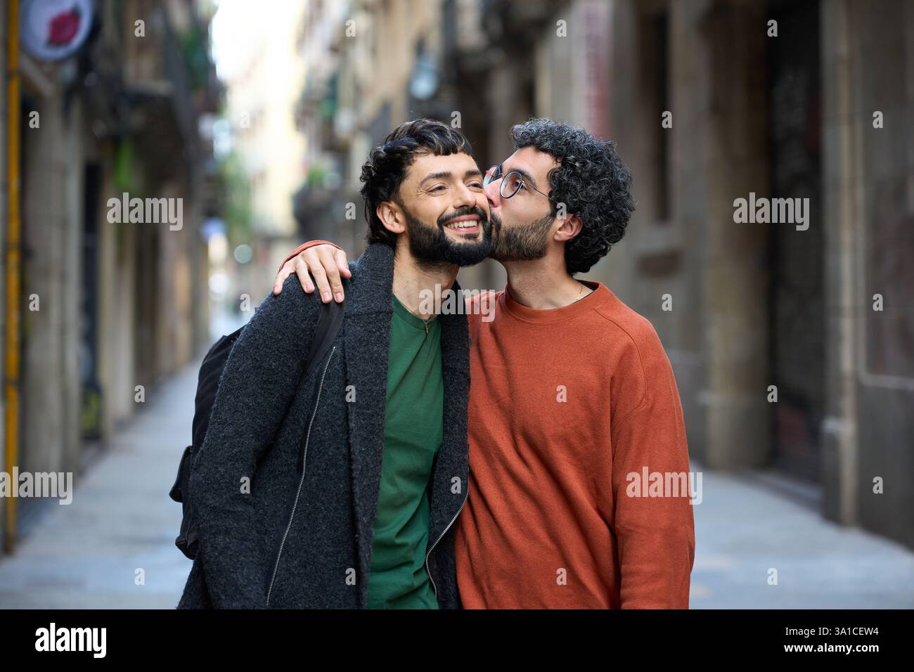 Gay couple kissing on cheek while walking down street Stock Photo - Alamy