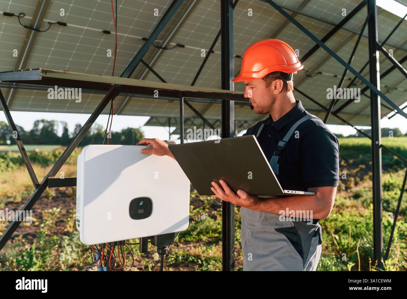 Standing and holding laptop. Man is doing operating and maintenance in ...