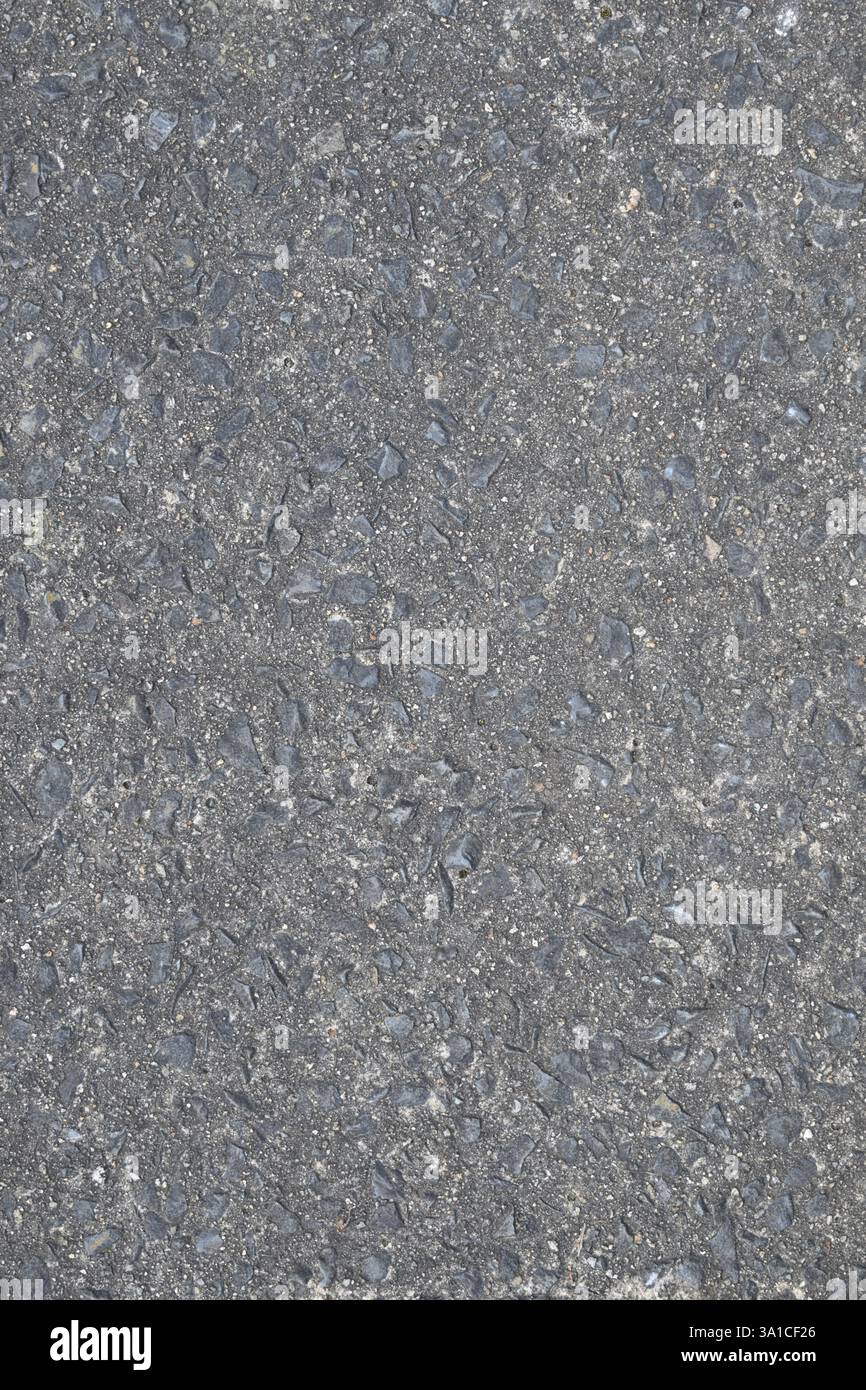 A grey and black pavement with a lot of gravel. The pavement is very ...