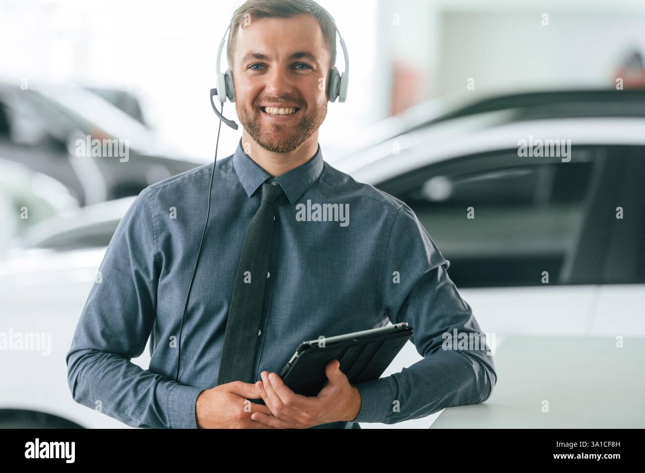 Manager is in the headphones and with notepad. Handsome car dealership ...