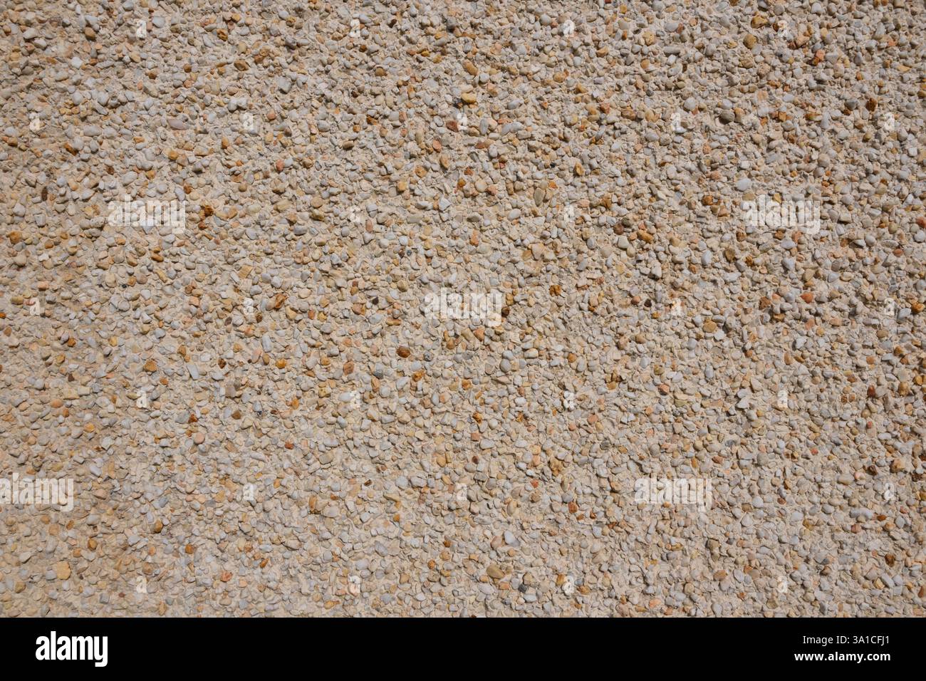 A wall with a lot of small rocks on it. The wall is tan in color. The ...