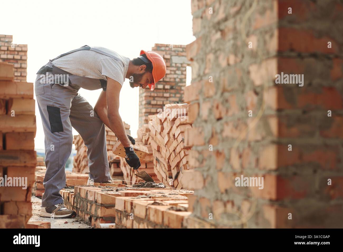 Bunch of bricks. Placing them. Handsome Indian man is on the ...