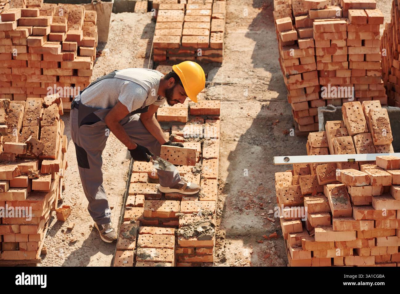 Bunch of bricks. Placing them. Handsome Indian man is on the ...