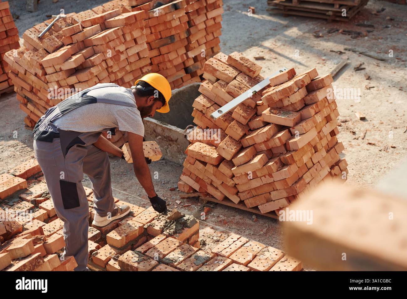 Bunch of bricks. Placing them. Handsome Indian man is on the ...