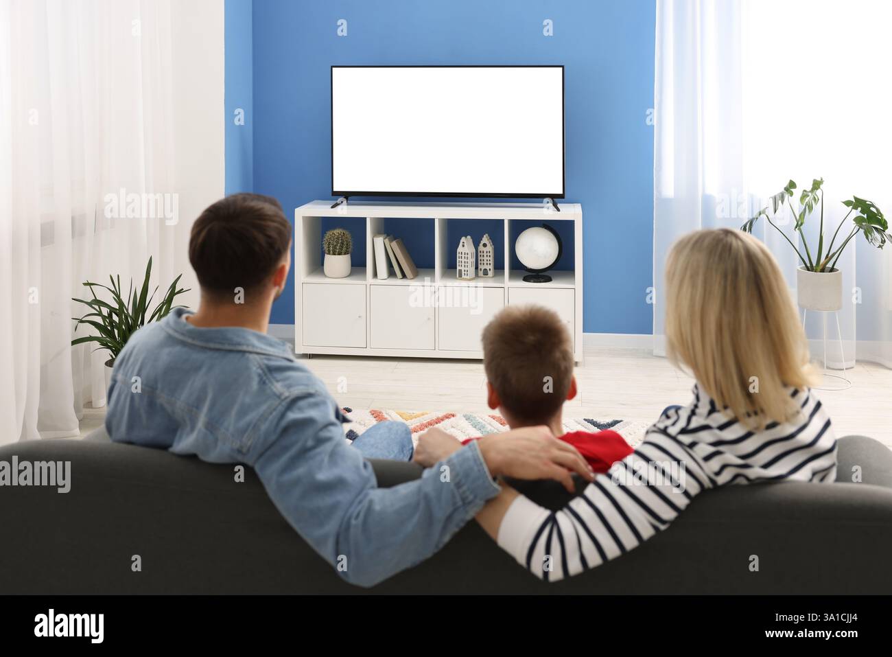Happy family watching tv together at home, back view Stock Photo - Alamy