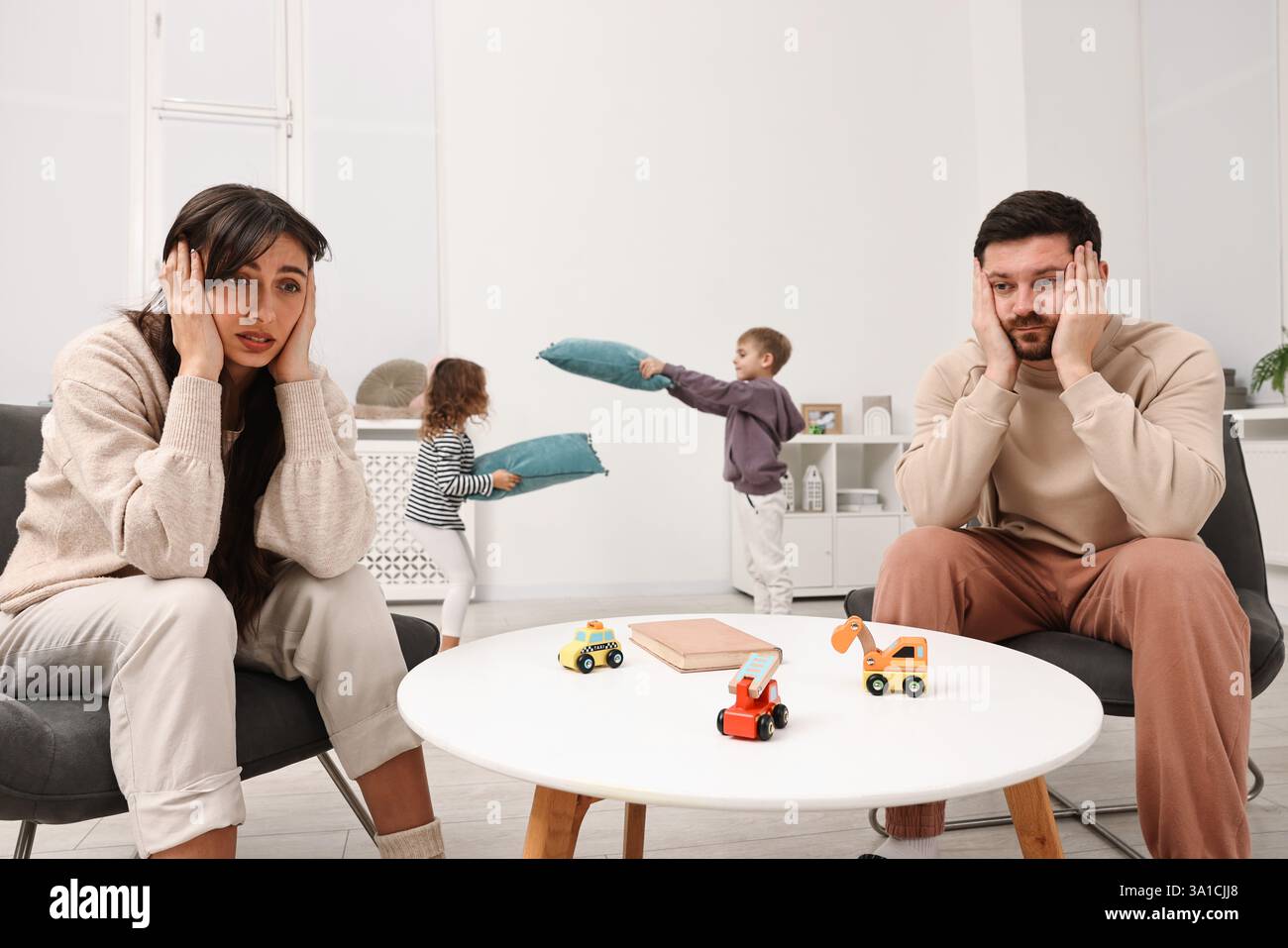Overwhelmed parents and their naughty children at home Stock Photo - Alamy