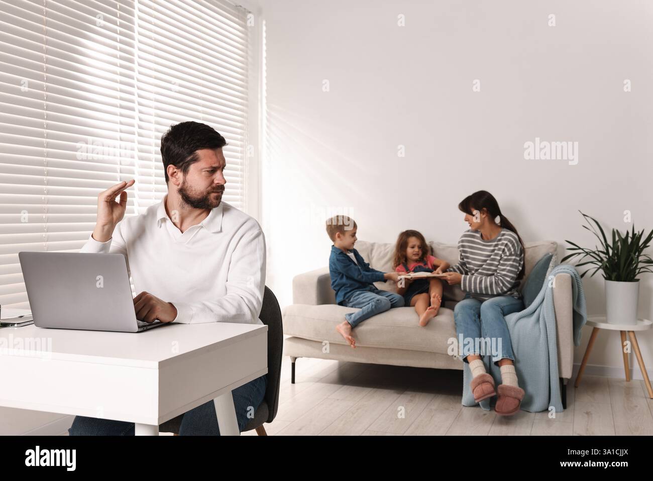 Noisy children with mother bothering their overwhelmed father at home ...