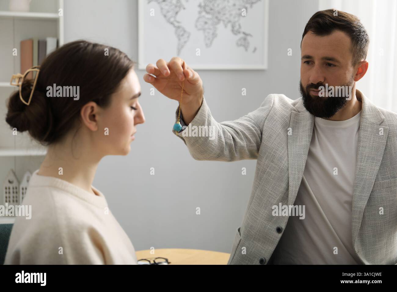 Psychologist using pendulum while working with patient during hypnosis ...