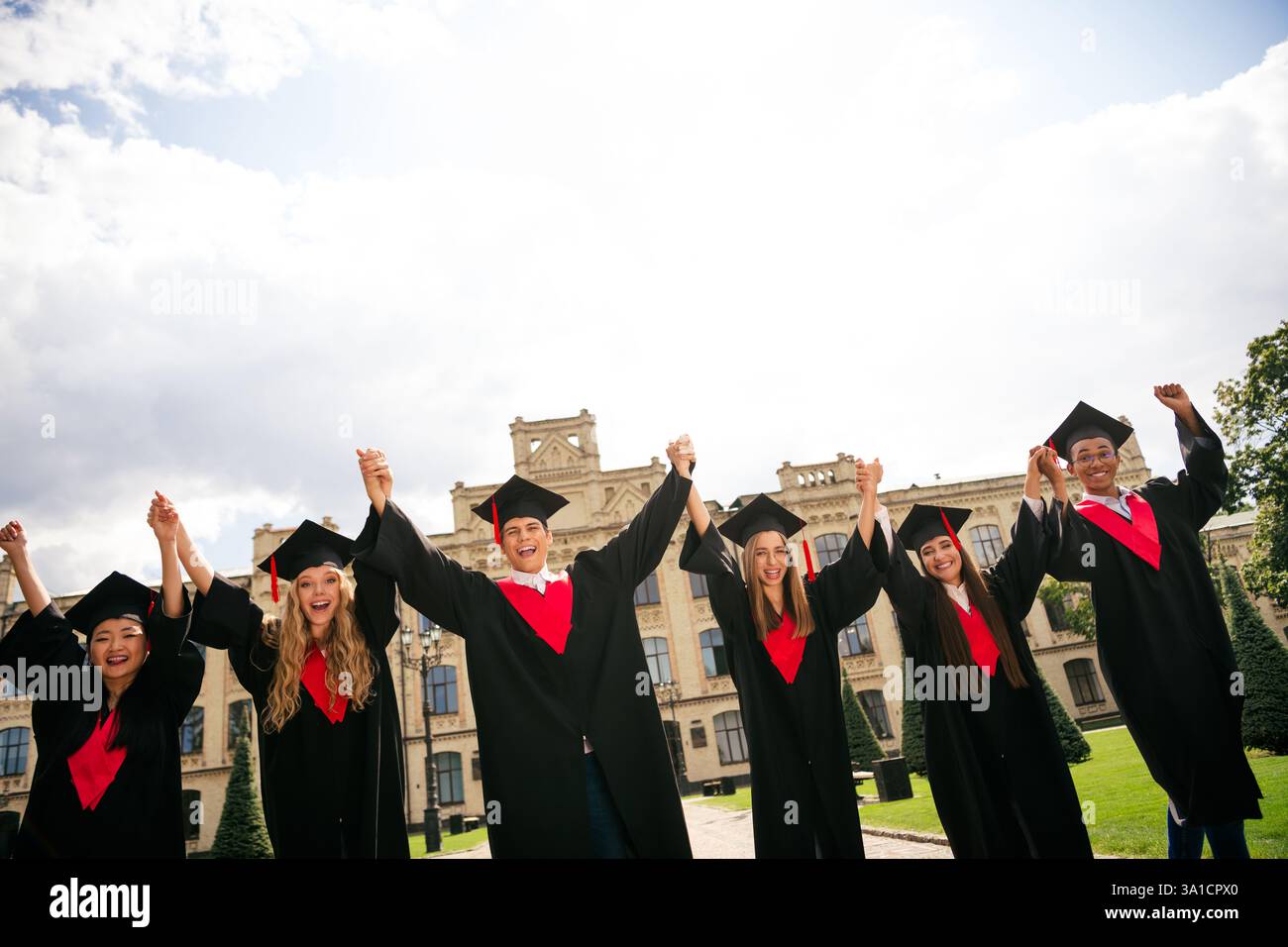 Group of young graduates celebrating in traditional caps and gowns in ...