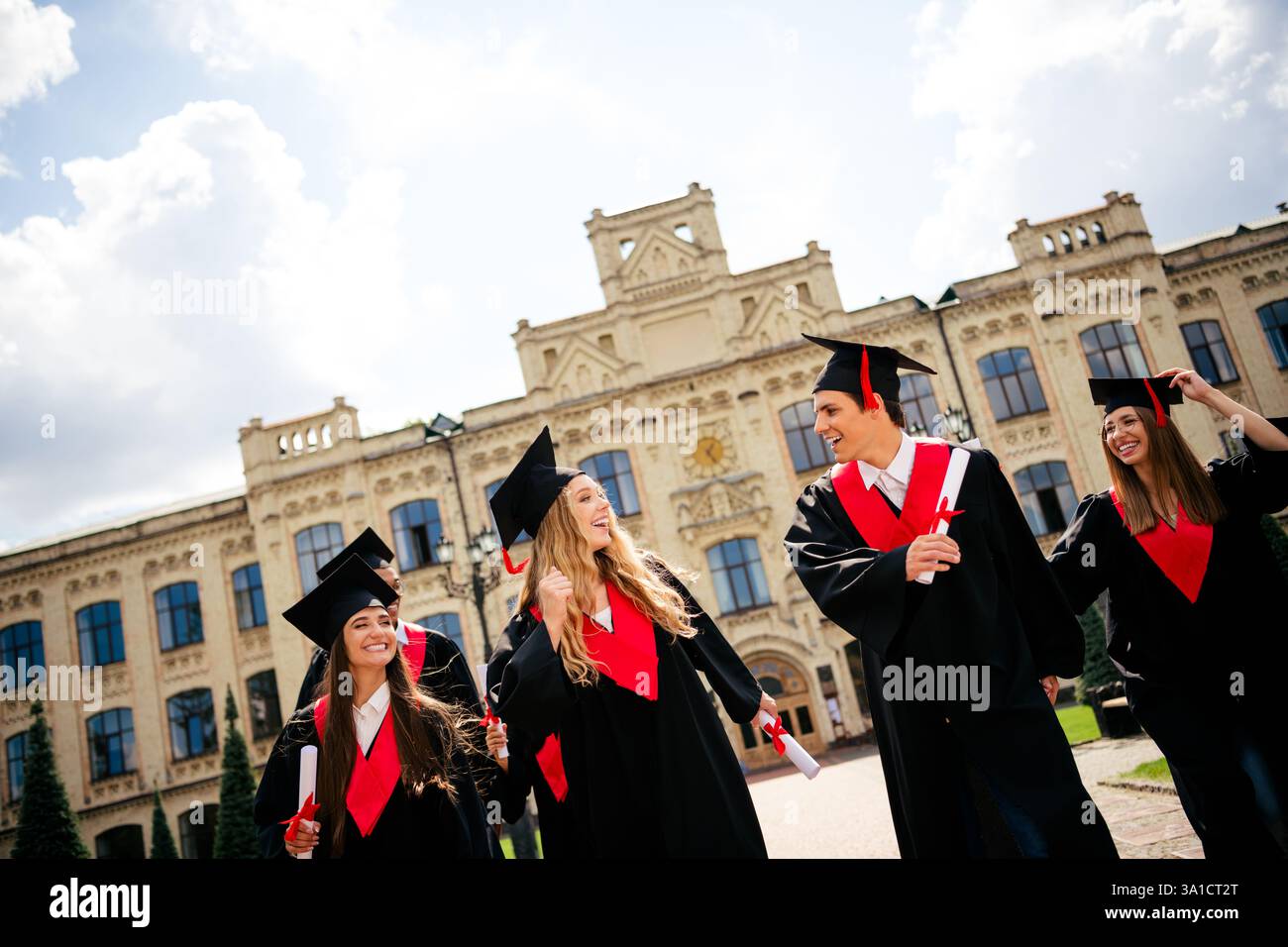 Joyful students celebrate graduation outdoors in summer sunlight ...