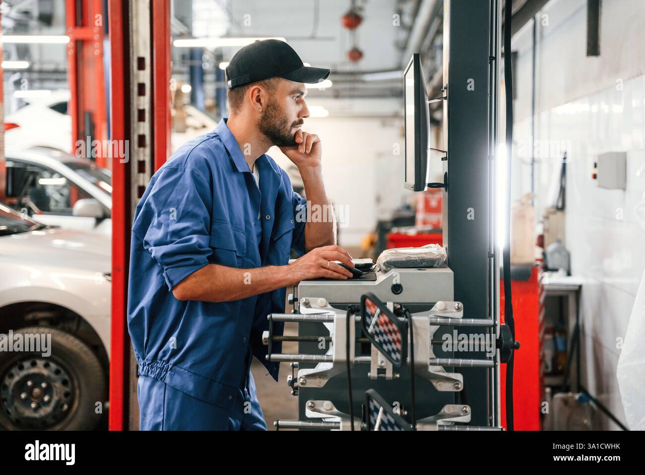 Standing by computer terminal. Auto mechanic working in garage. Repair ...