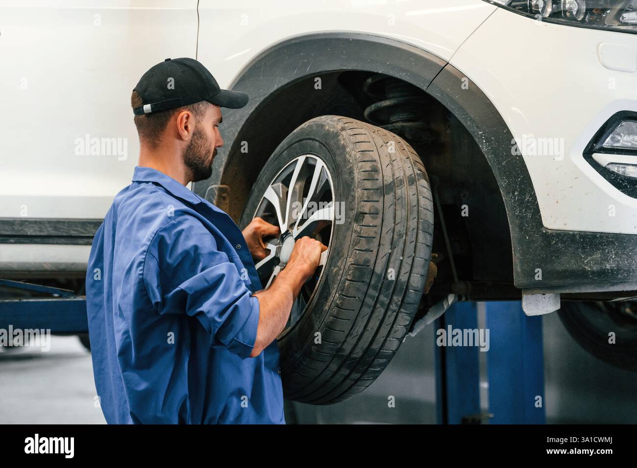 Setting up new wheel. Auto mechanic working in garage. Repair service ...