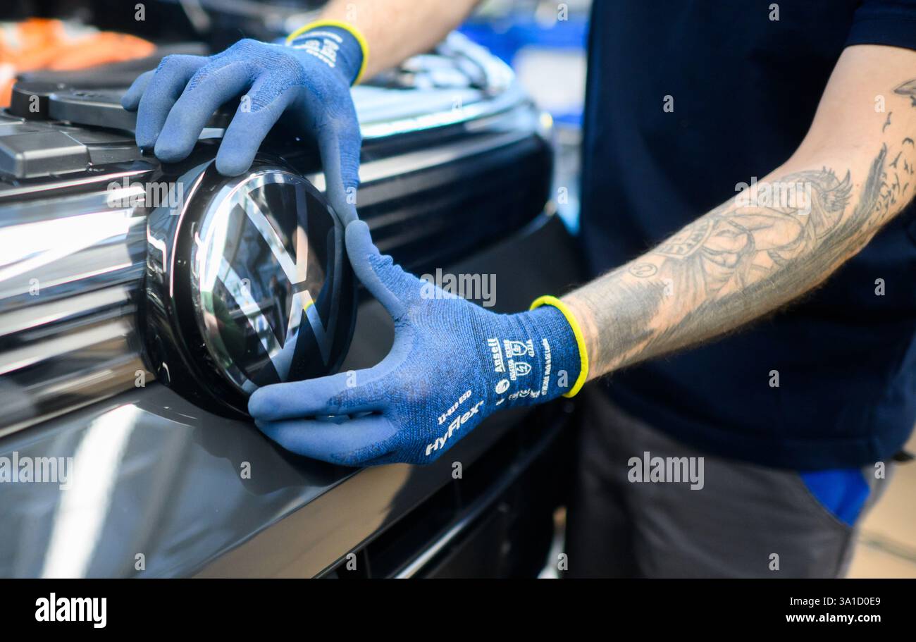 PRODUCTION - 07 March 2025, Lower Saxony, Wolfsburg: An employee mounts ...