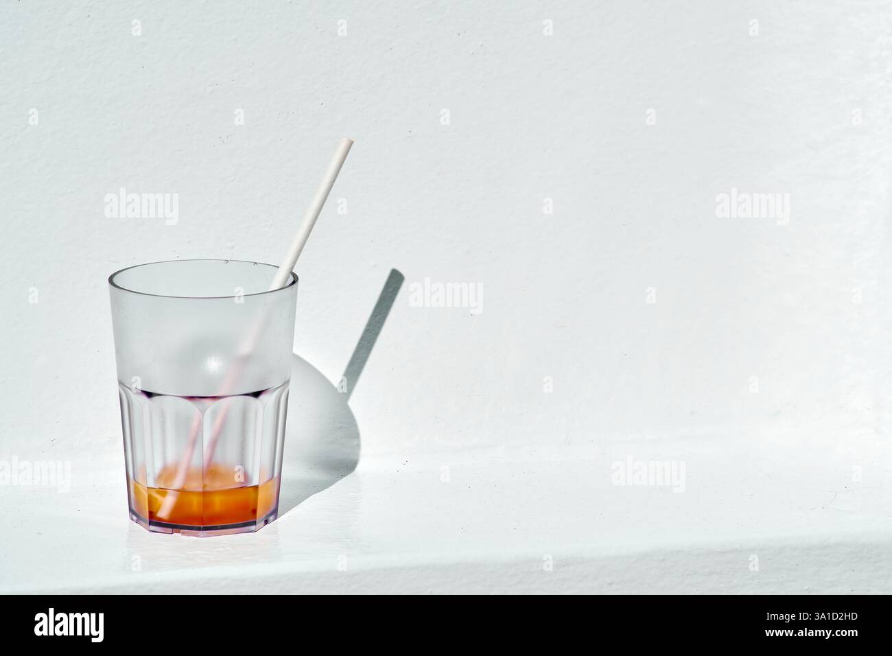 Nearly empty beverage glass with a colorful straw and traces of orange ...