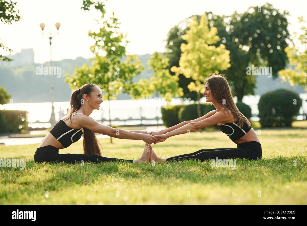 Holding each other by hands, touching feet. Two women in sport clothes ...