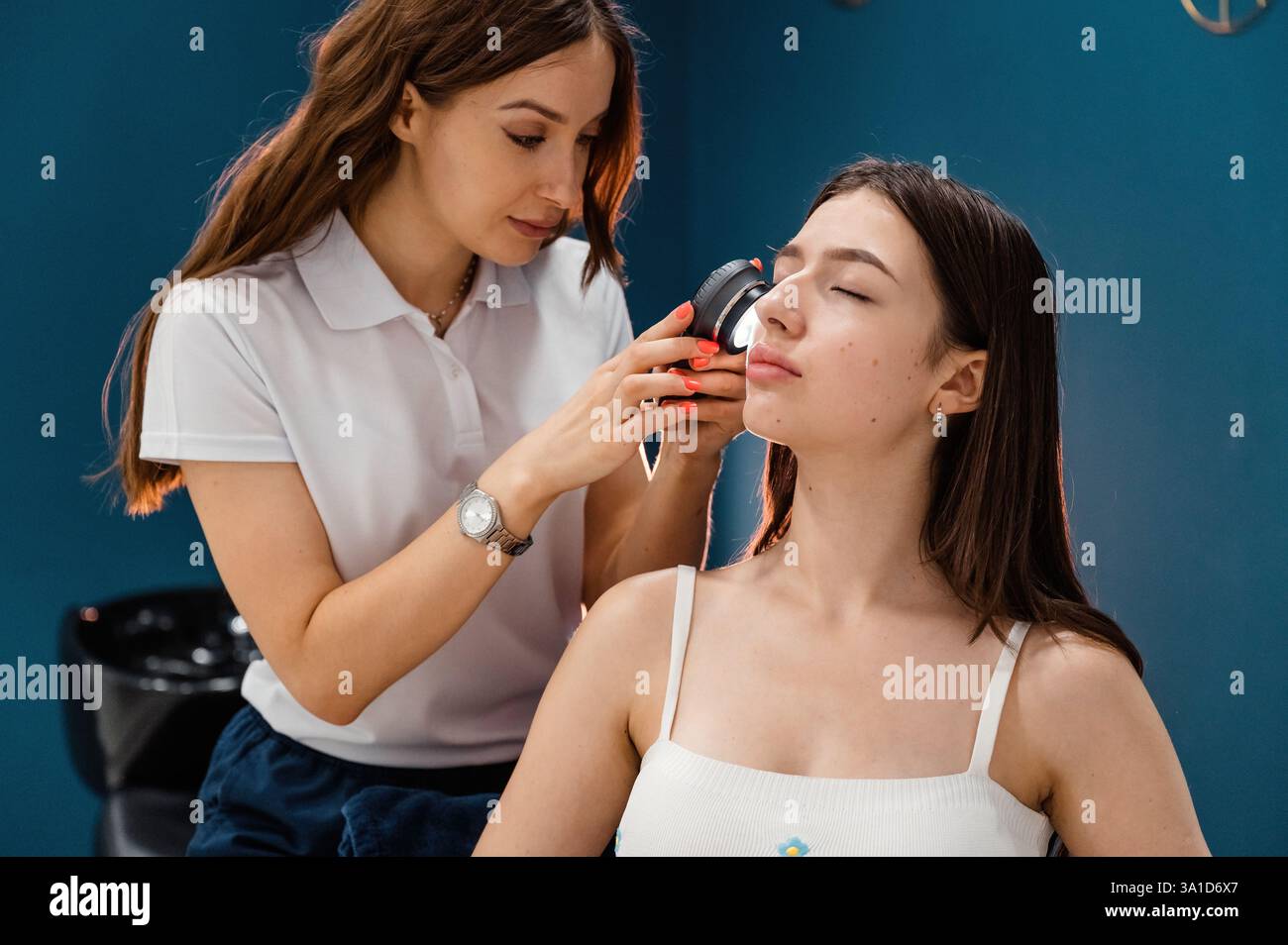 Beauty salon worker is examining skin of the woman by using a device ...