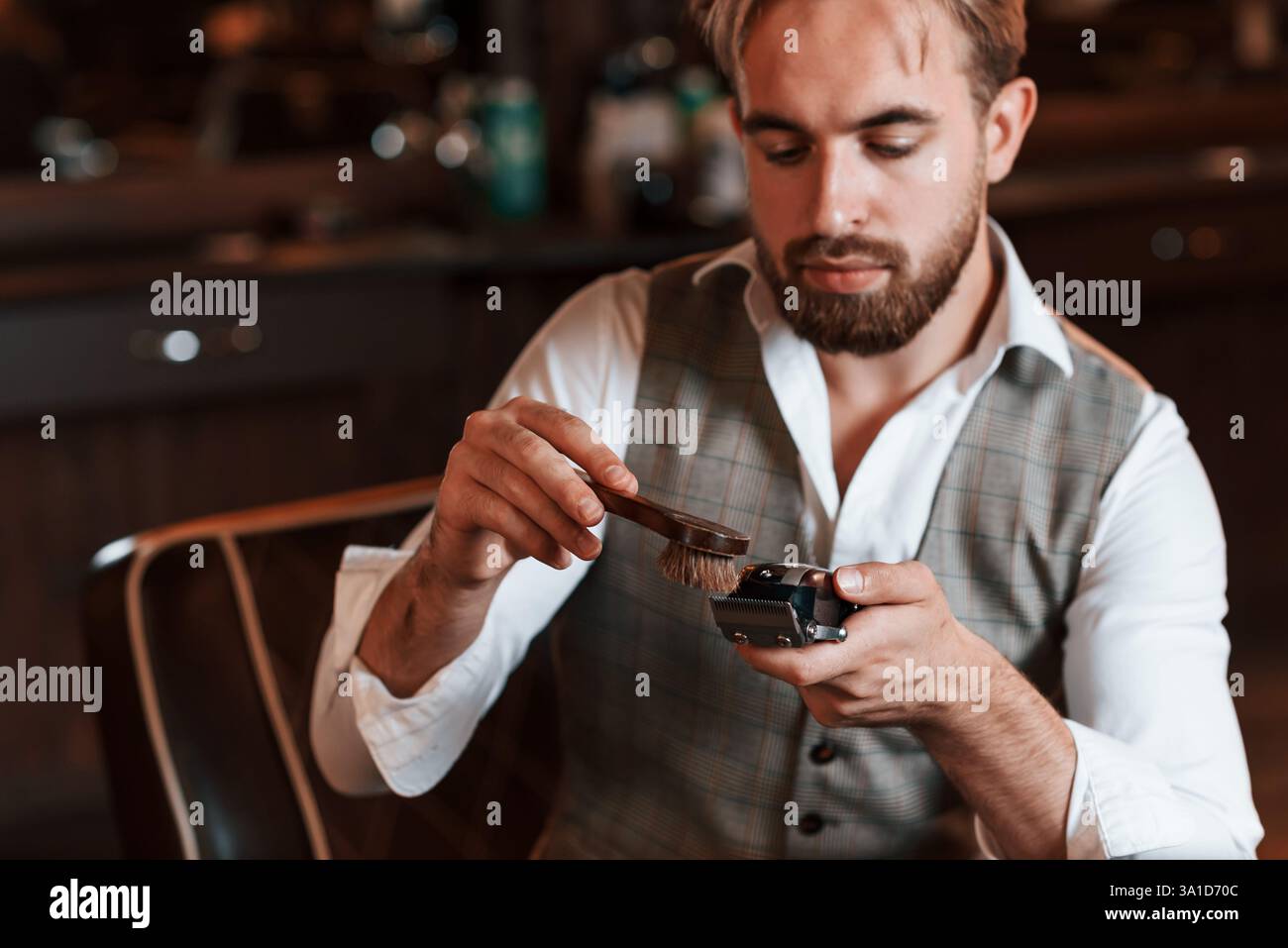 Cleaning hair clipper. Handsome barber is in the salon Stock Photo - Alamy