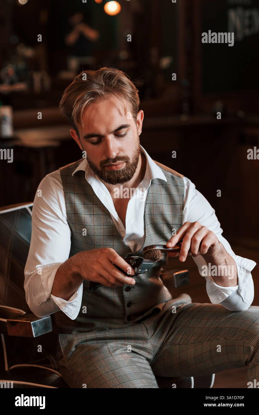 Process of cleaning hair clipper. Handsome barber is in the salon Stock ...