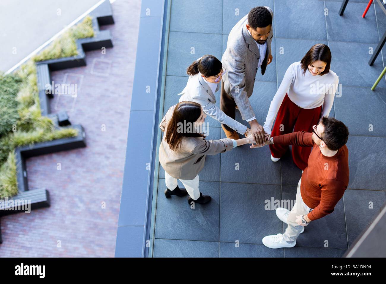 Five friends engage in an enthusiastic group handshake, showcasing ...