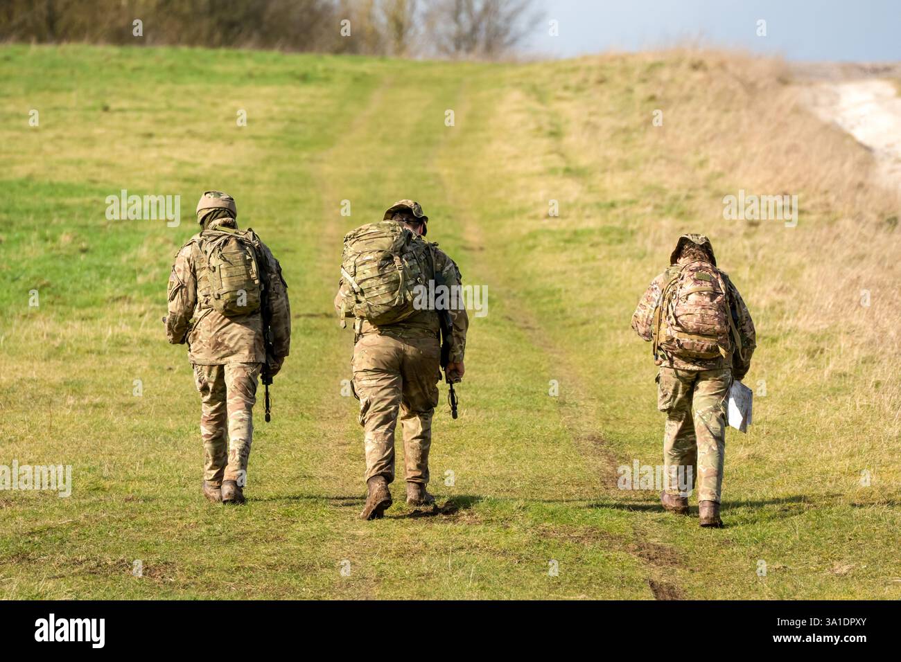 Three British army male and female soldiers tabbing bearing full 40Kg ...
