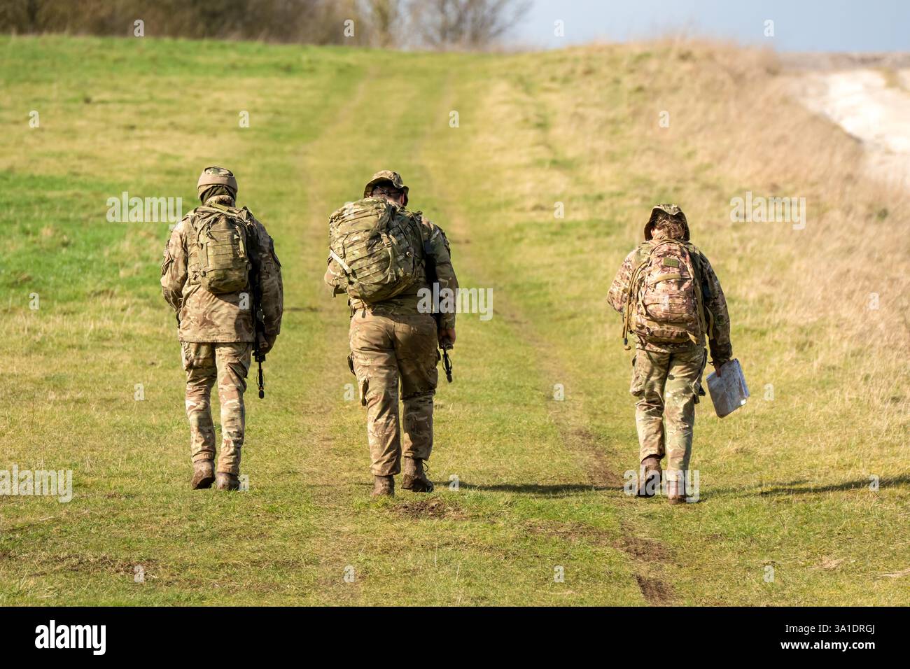 Three British army male and female soldiers tabbing bearing full 40Kg ...
