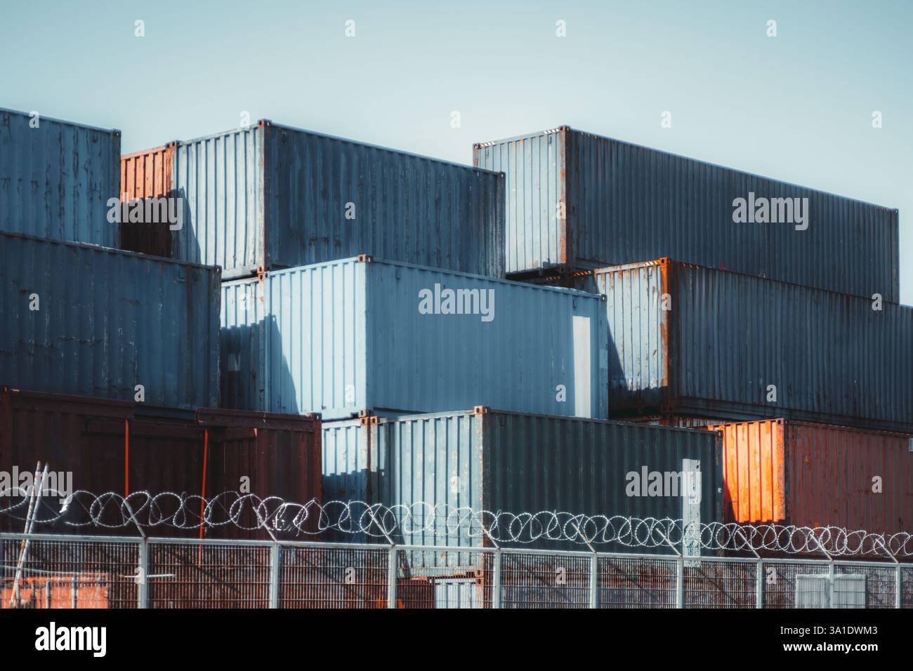 Stacked metal shipping containers with visible rust and wear, secured ...