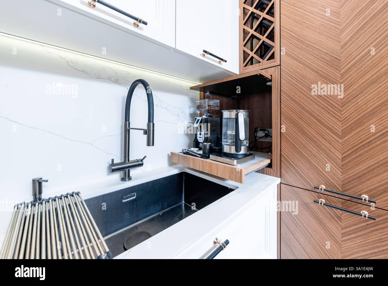 A kitchen sink with a coffee maker on top of it. The sink is black and ...