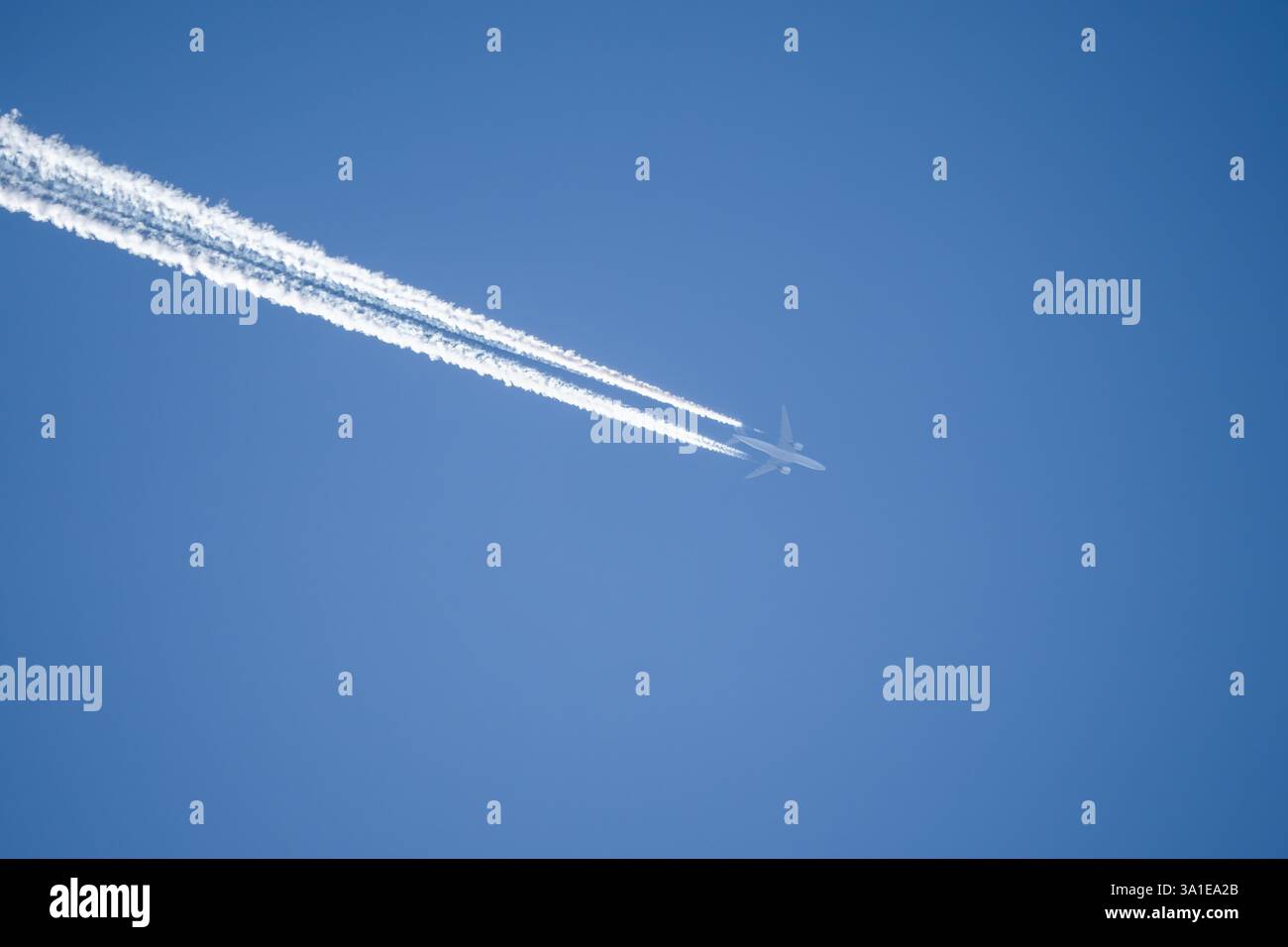 a twin engined jet liner aircraft in deep blue sky, contrails vapour ...