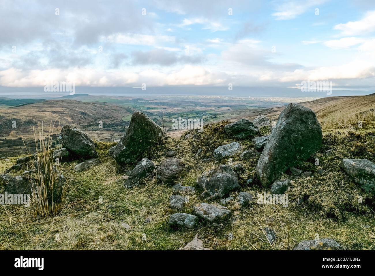 Open landscape. Rocks form a small cluster on a hill. Extensive flat ...