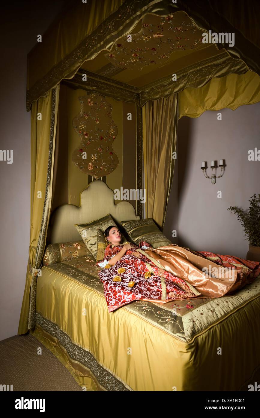 Golden medieval bedroom with beautiful canopy bed. A lady in ...