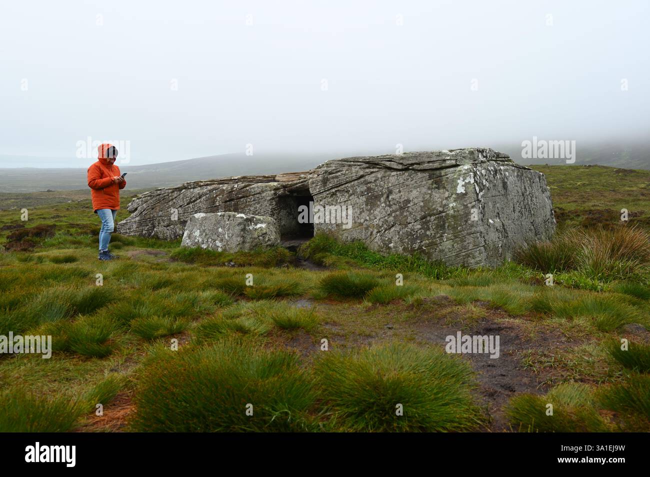 person photographing Dwarfie Stane, prehistoric tomb carved from ...