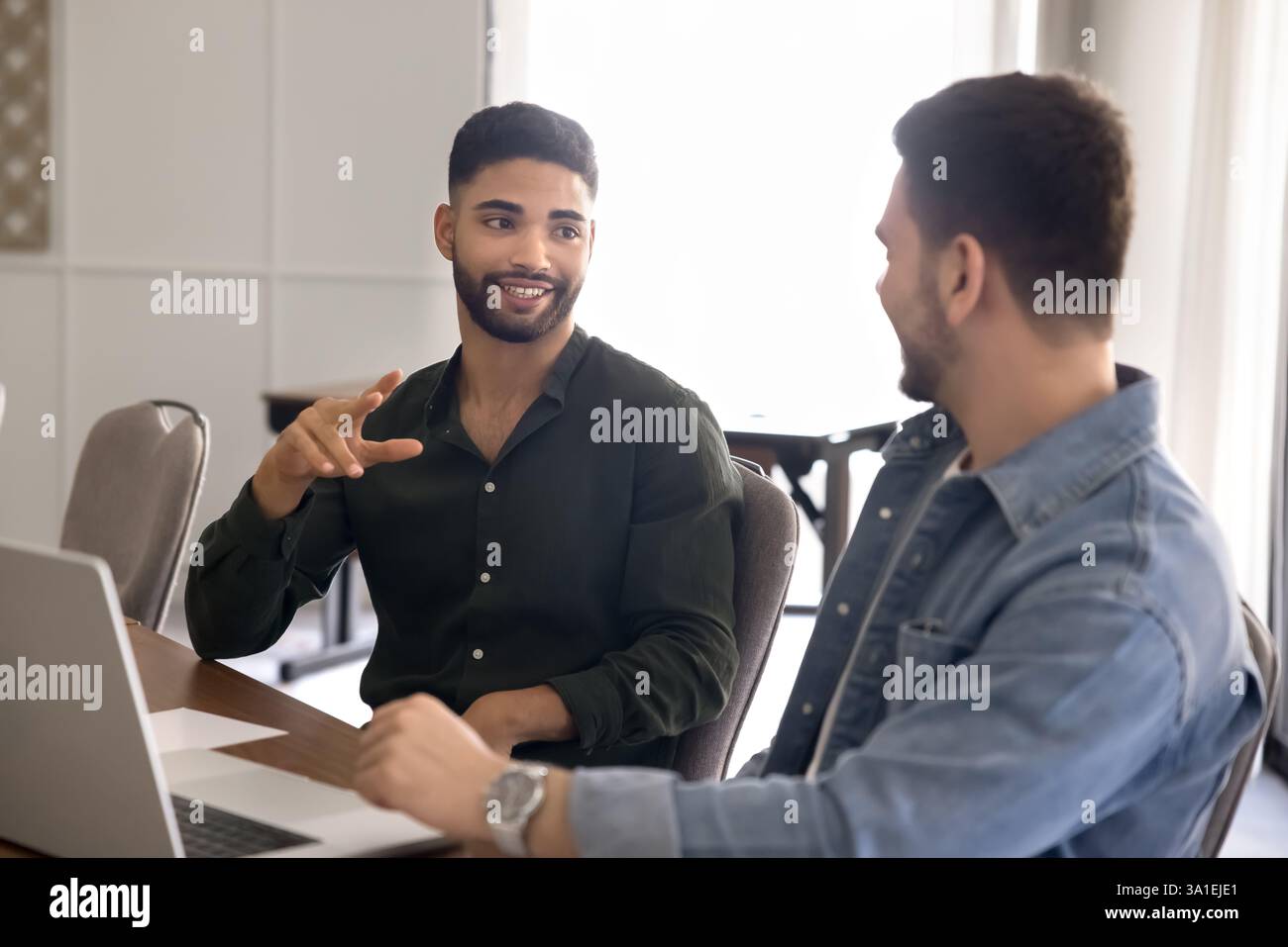 Two male teammates engaged in talk seated in office boardroom Stock ...