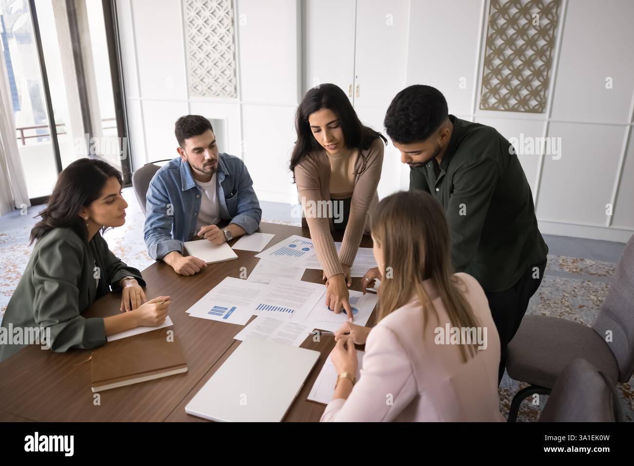 Professionals gathered around conference table, engaged in paperwork ...