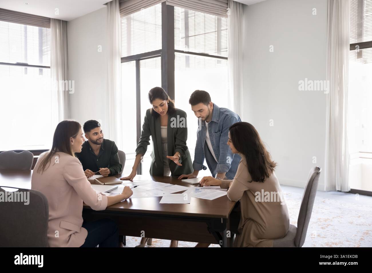 Professionals doing data analysis, reviewing papers laid out on table ...