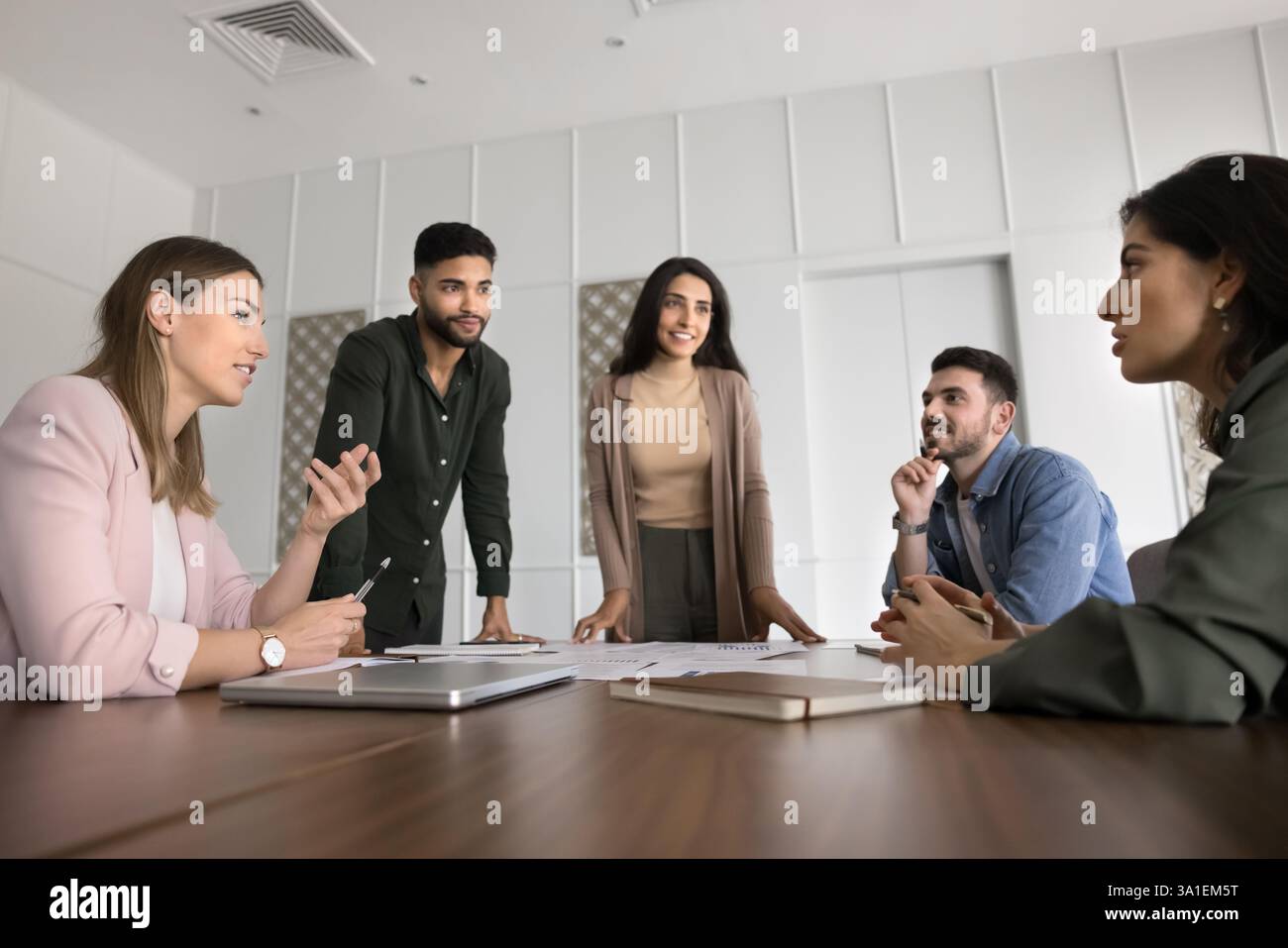 Team engaged in brainstorming gathered around conference table with ...