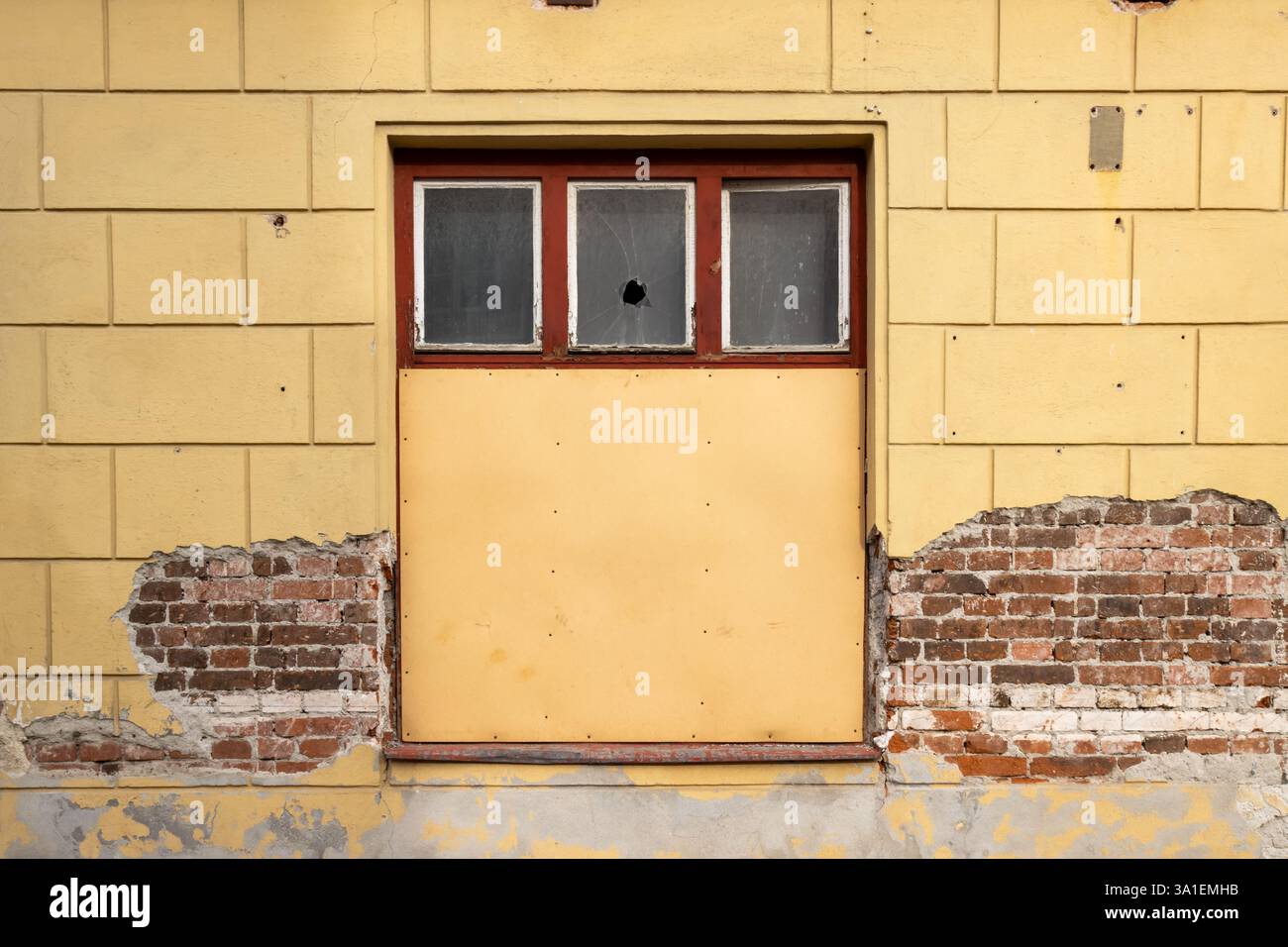 Old facade with peeled-off parts with visible bricks. Covered window by ...