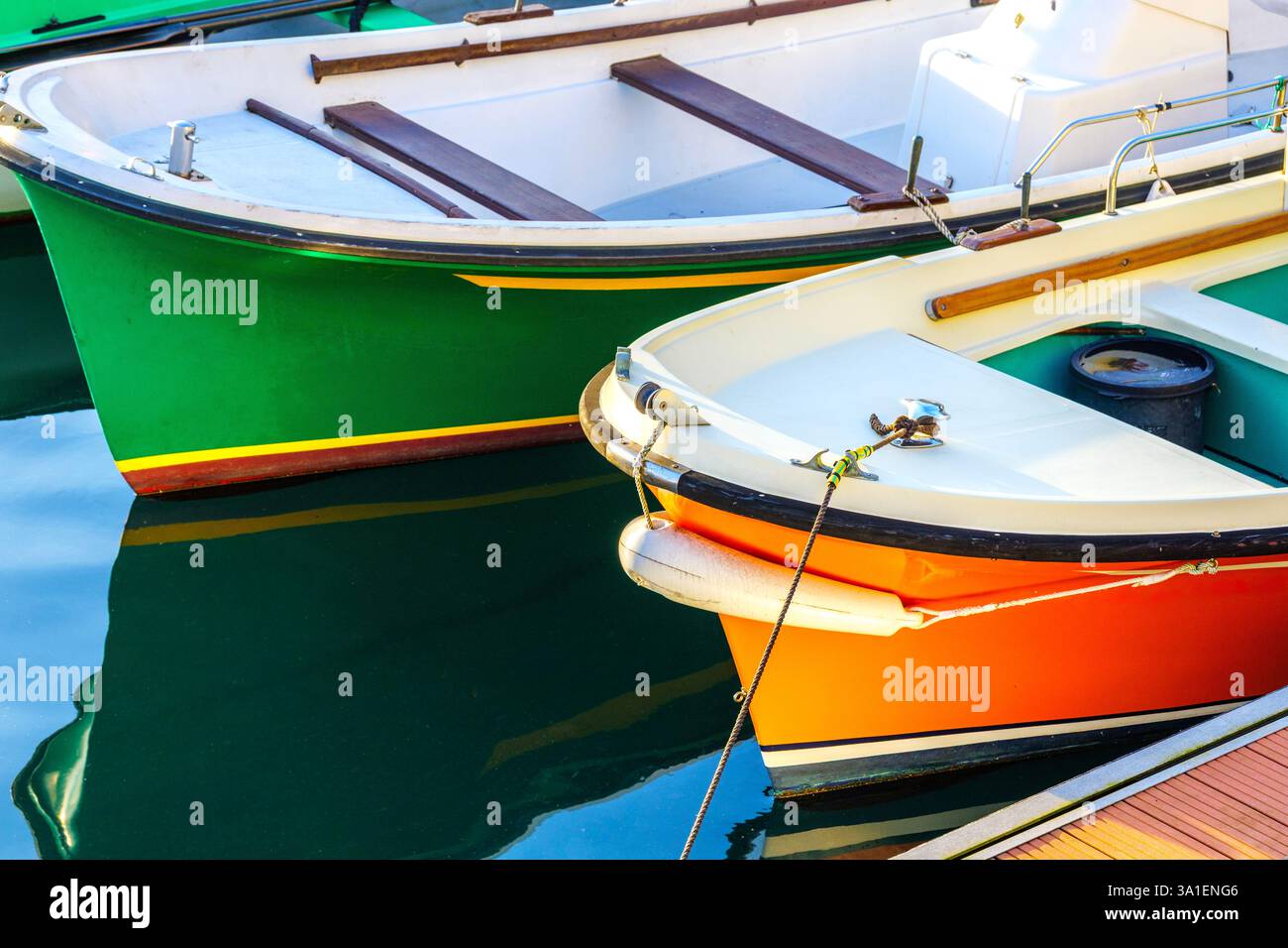 Small fishing boats moored in calm harbor waters, reflecting their ...