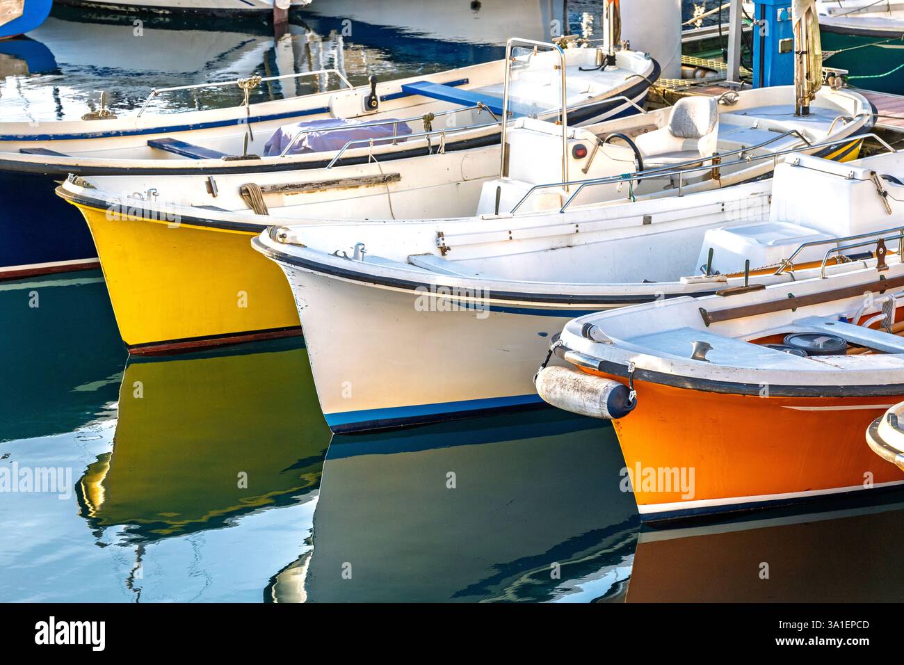 Small fishing boats moored in calm harbor waters, reflecting their ...