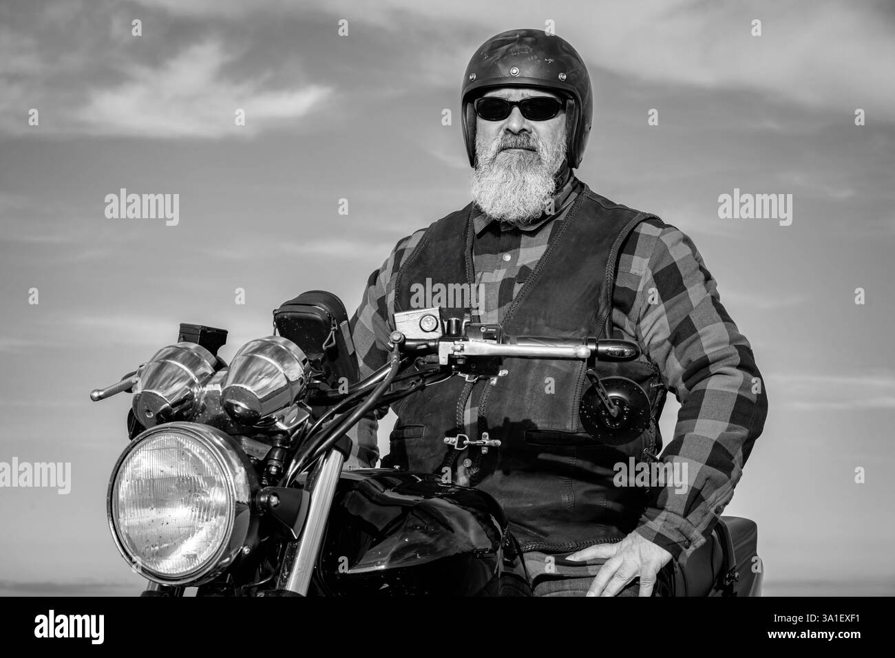 Cooler Rocker mit grauem Bart und Sonnenbrille sitzt auf seiner ...