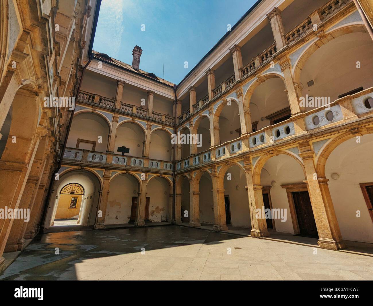 A historic courtyard with multiple levels of arches and columns ...