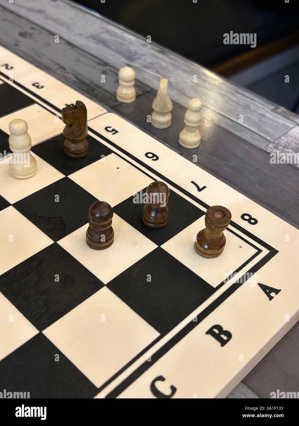 wooden chess board with game pieces on the textured black and white ...