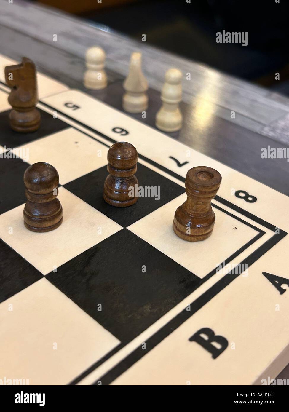 wooden chess board with game pieces on the textured black and white ...