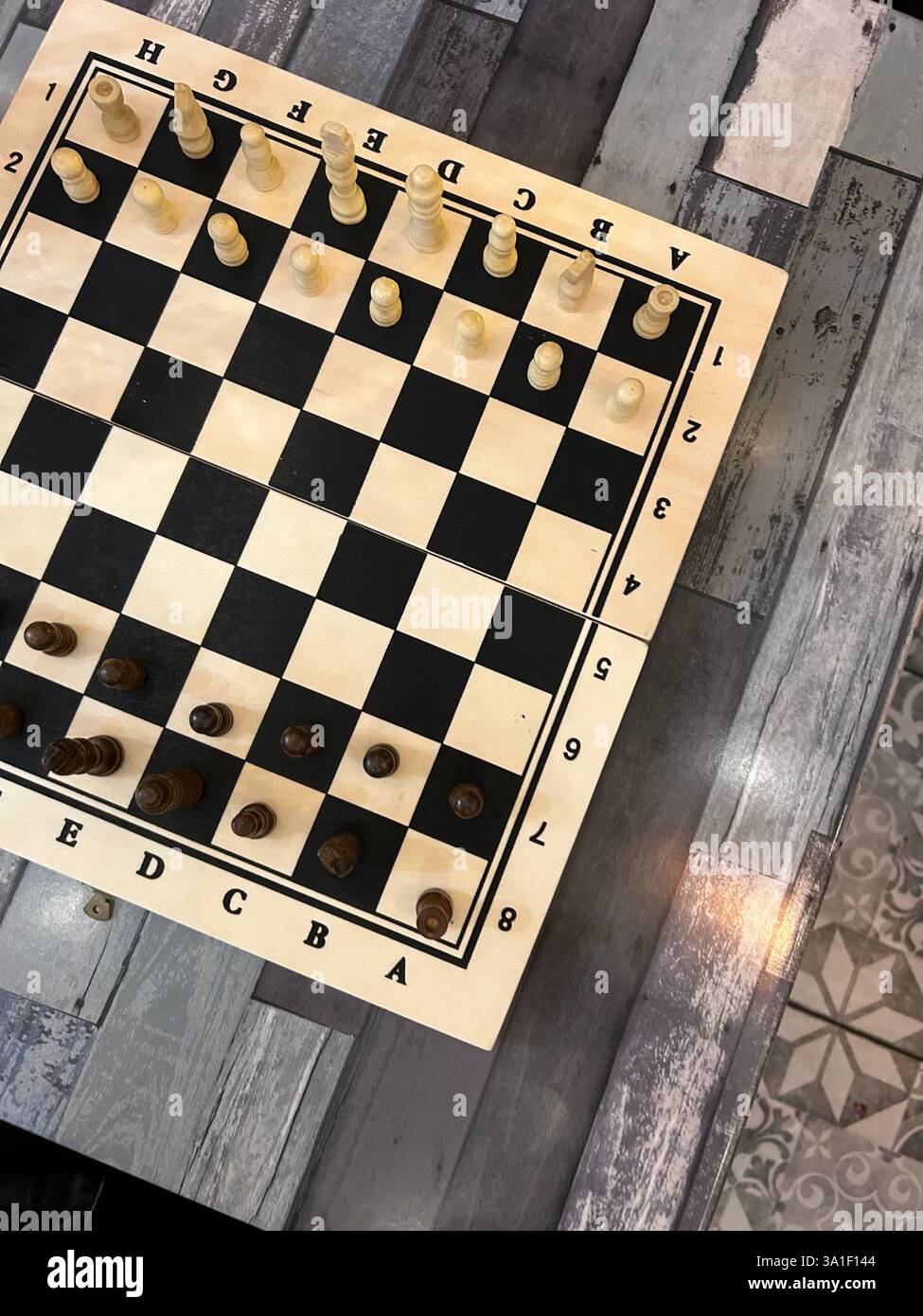 wooden chess board with game pieces on the textured black and white ...