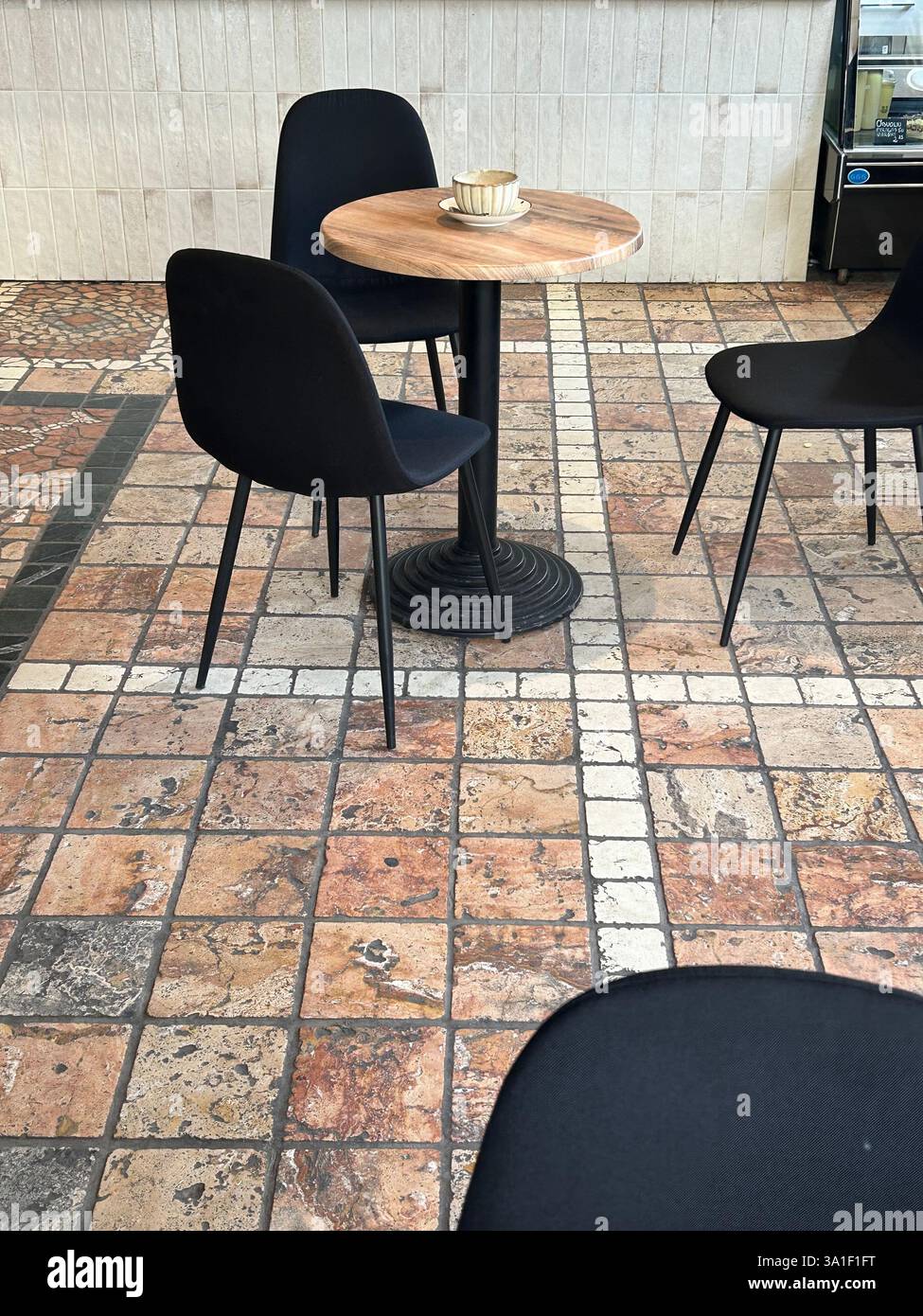 A wooden table with a few black chairs at the restaurant outdoors ...