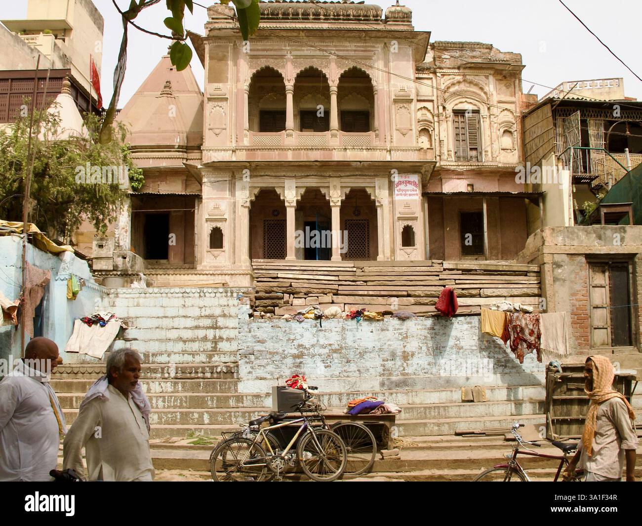 Daily street life unfolds before a faded haveli in Varanasi, where ...