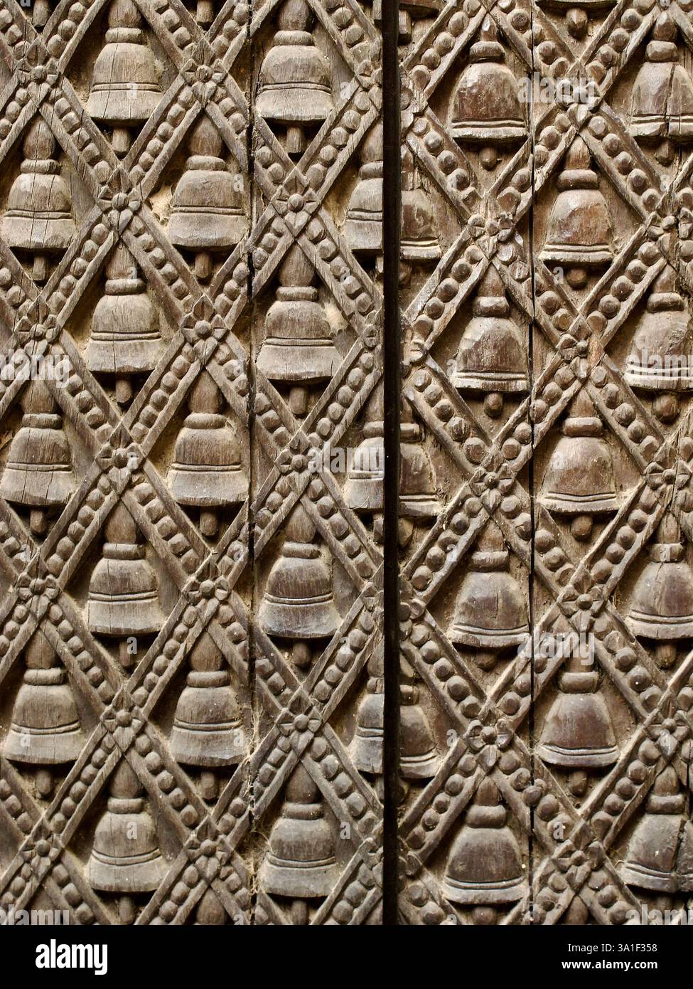 Intricately carved wooden door featuring temple bell motifs at the ...