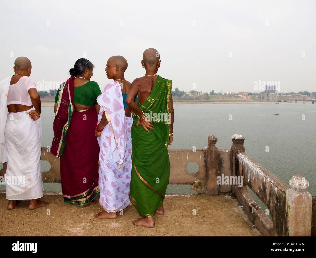 Female pilgrims with shaved heads overlook the Ganges from Ramnagar ...