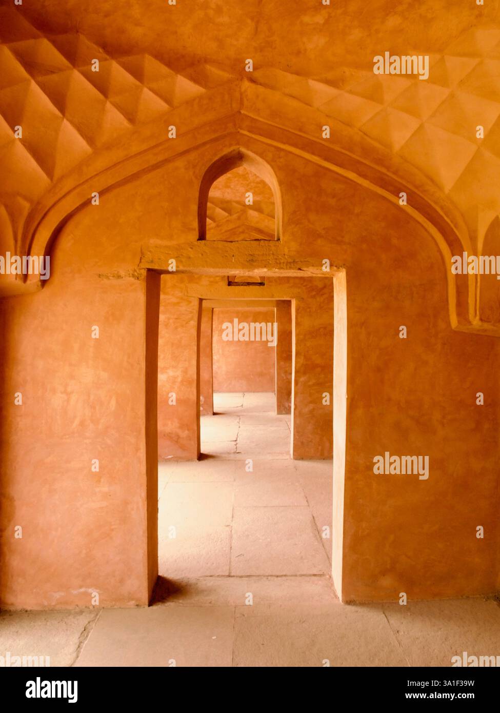 Red sandstone corridor with arched niches and geometric ceiling detail ...
